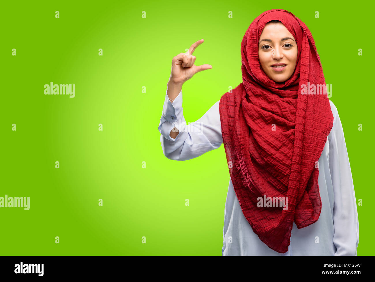 Young arab woman wearing hijab holding something very tiny, size ...