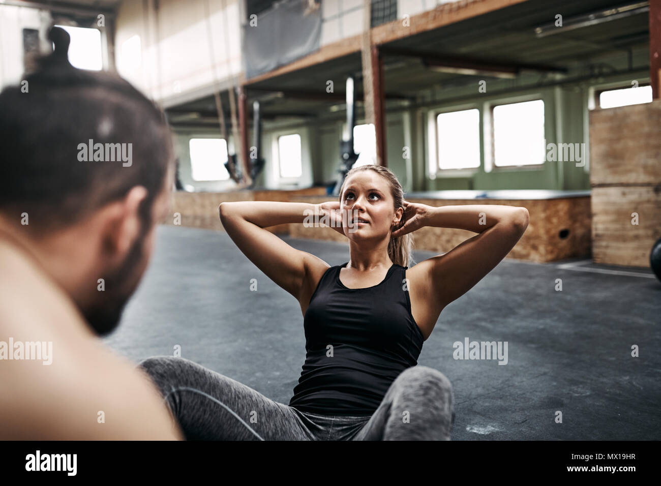 Fit young woman doing crunches with a male exercise partner on the ...