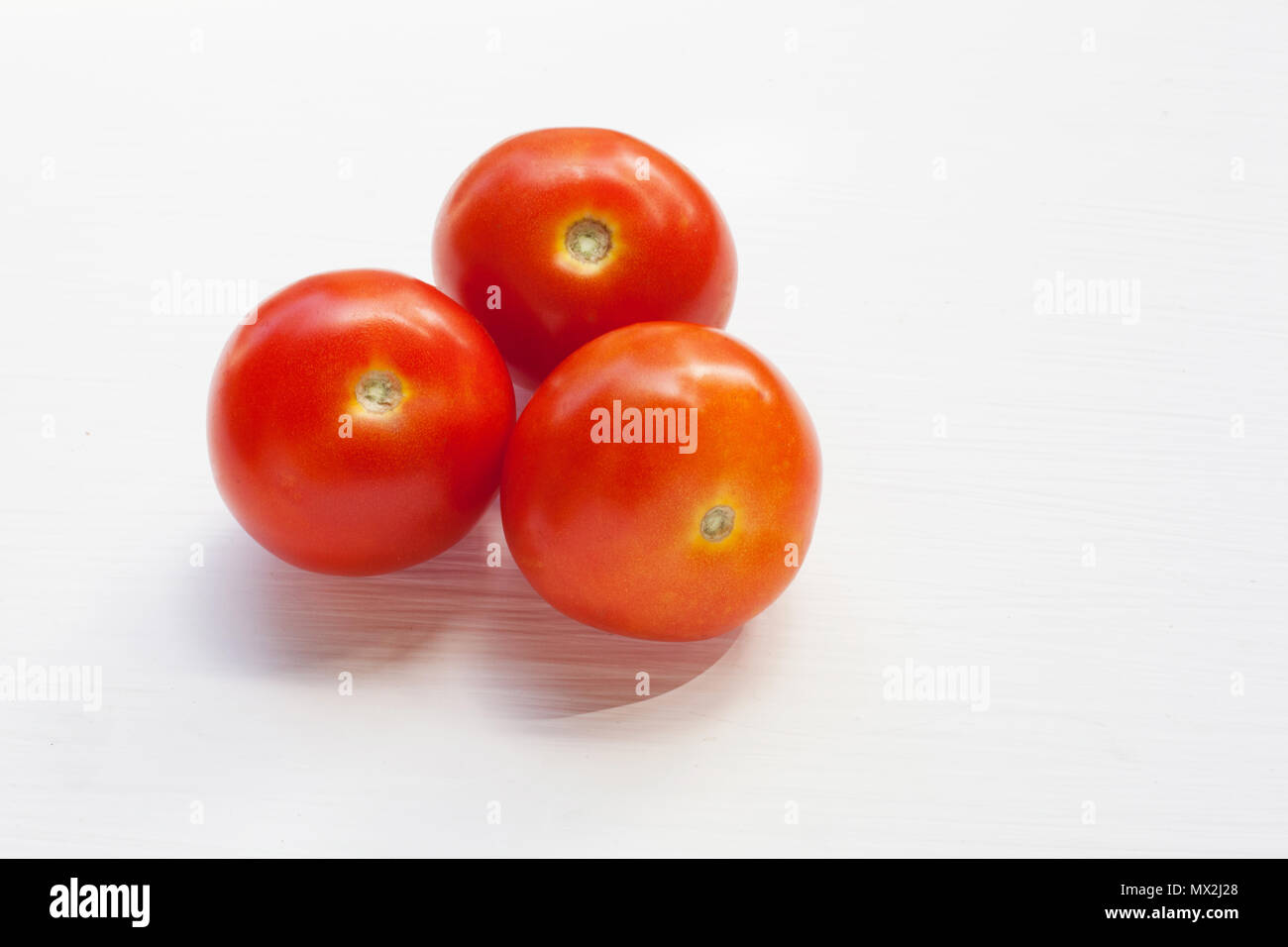 Three red tomatoes on a white background Stock Photo - Alamy
