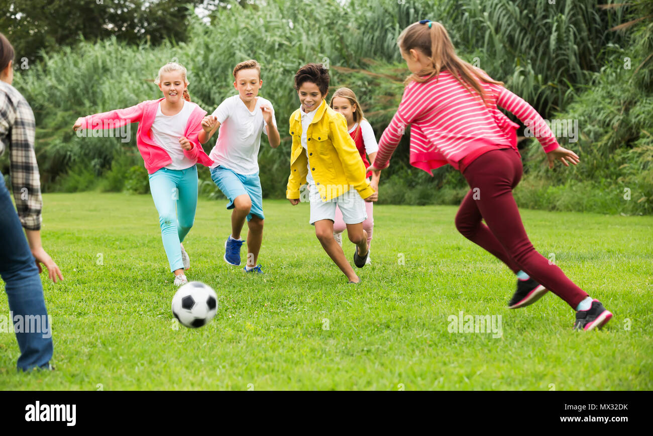 Company of smiling kids playing football on the playground in park ... Company of smiling kids playing football on the playground in park ...