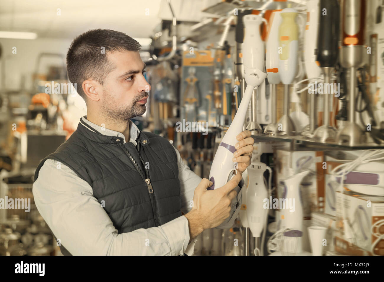 Positive male is standing with new mixer for his home in the store ...