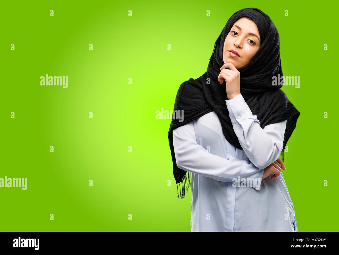 Young arab woman wearing hijab thinking and looking up expressing doubt ...