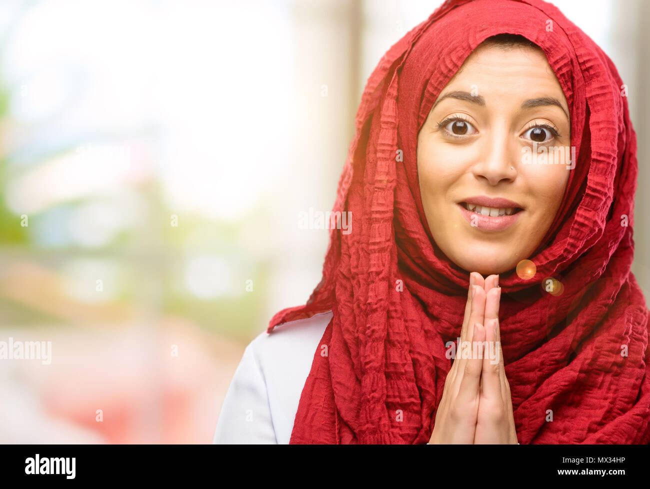 Young arab woman wearing hijab with hands together in praying gesture ...