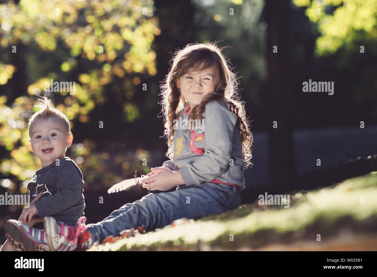 Happy children playing on green grass in spring park Stock Photo - Alamy