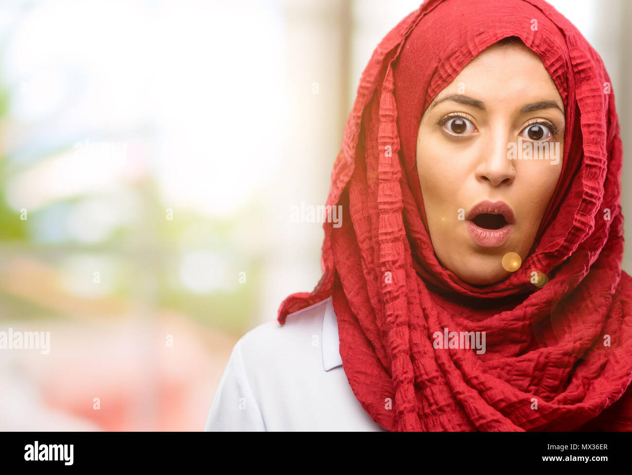 Young arab woman wearing hijab scared and surprised cheering expressing ...