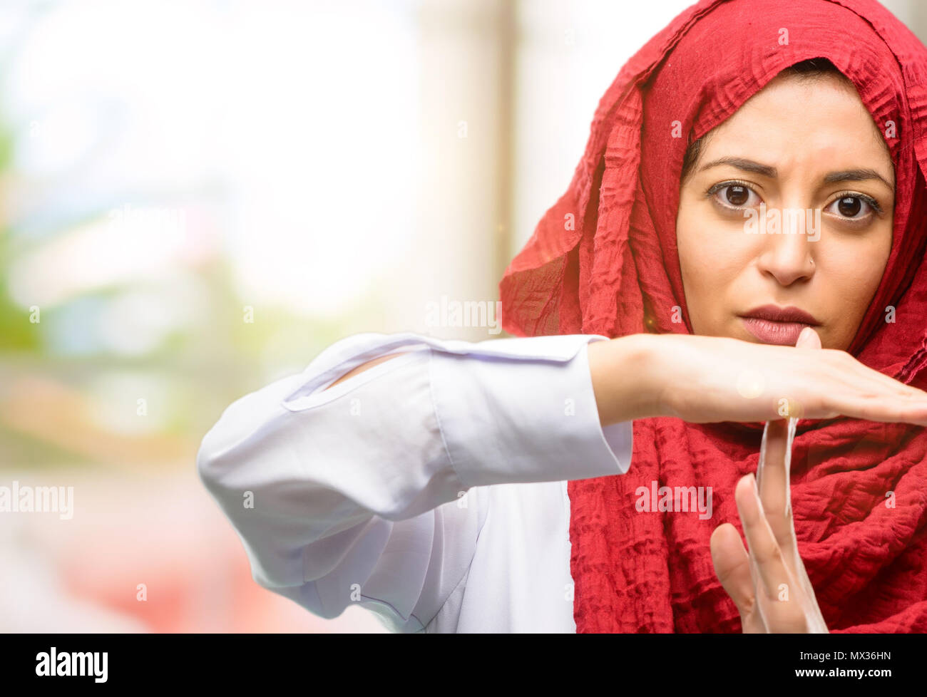 Young arab woman wearing hijab serious making a time out gesture with ...