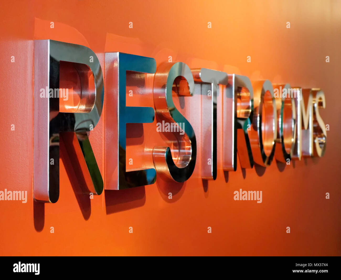 Restrooms text on orange wall Stock Photo - Alamy