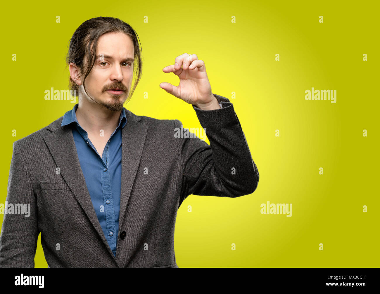 Handsome young man holding something very tiny, size concept Stock ...