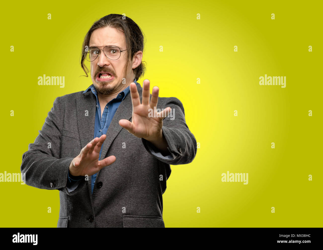 Handsome young man disgusted and angry, keeping hands in stop gesture ...