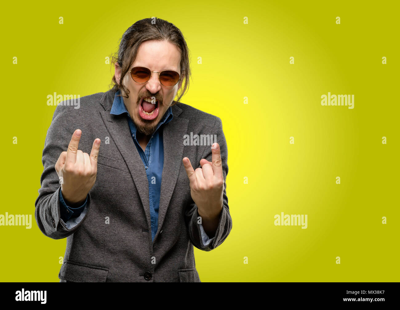 Handsome young man making rock symbol with hands, shouting and ...