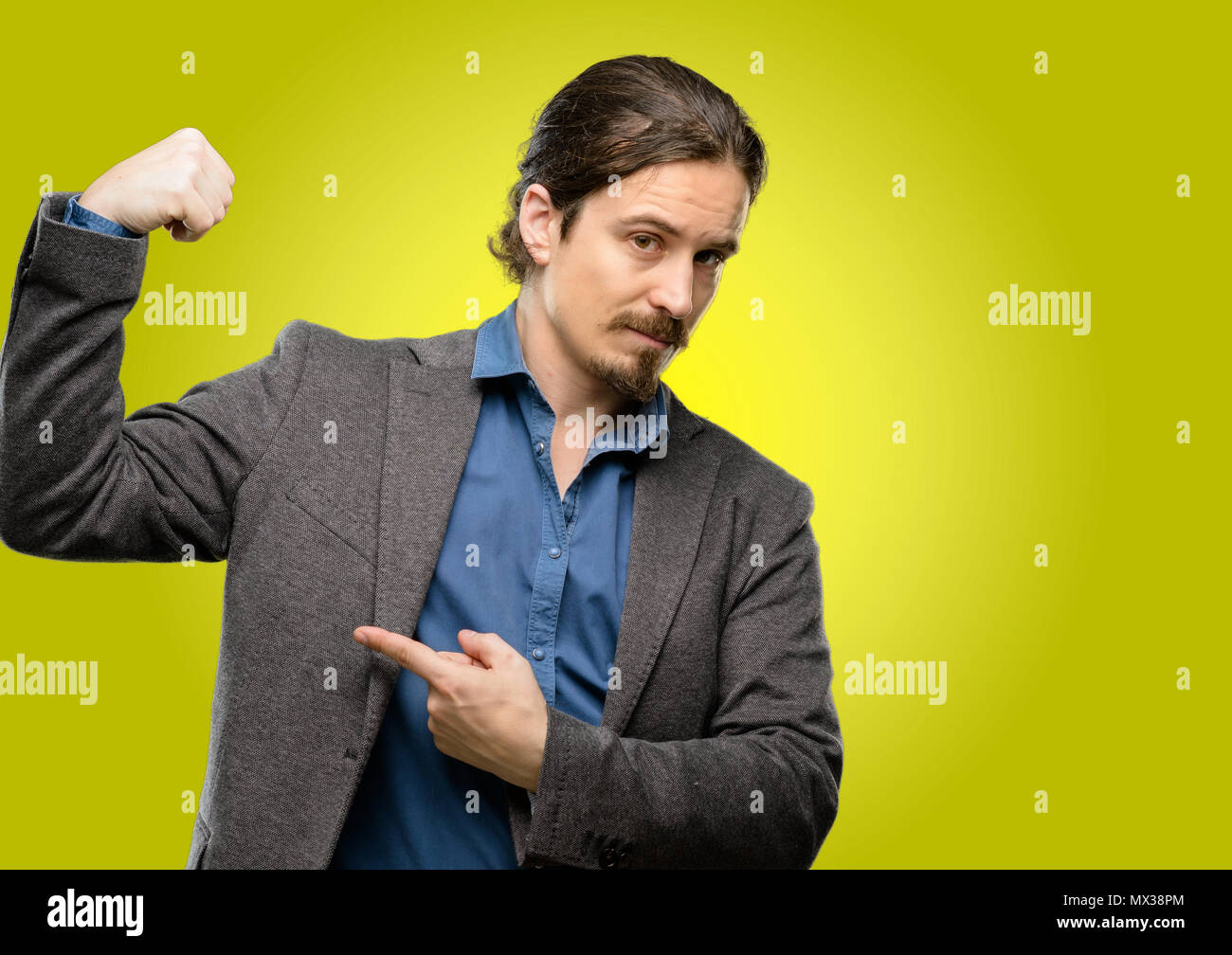 Handsome young man pointing biceps expressing strength and gym concept ...