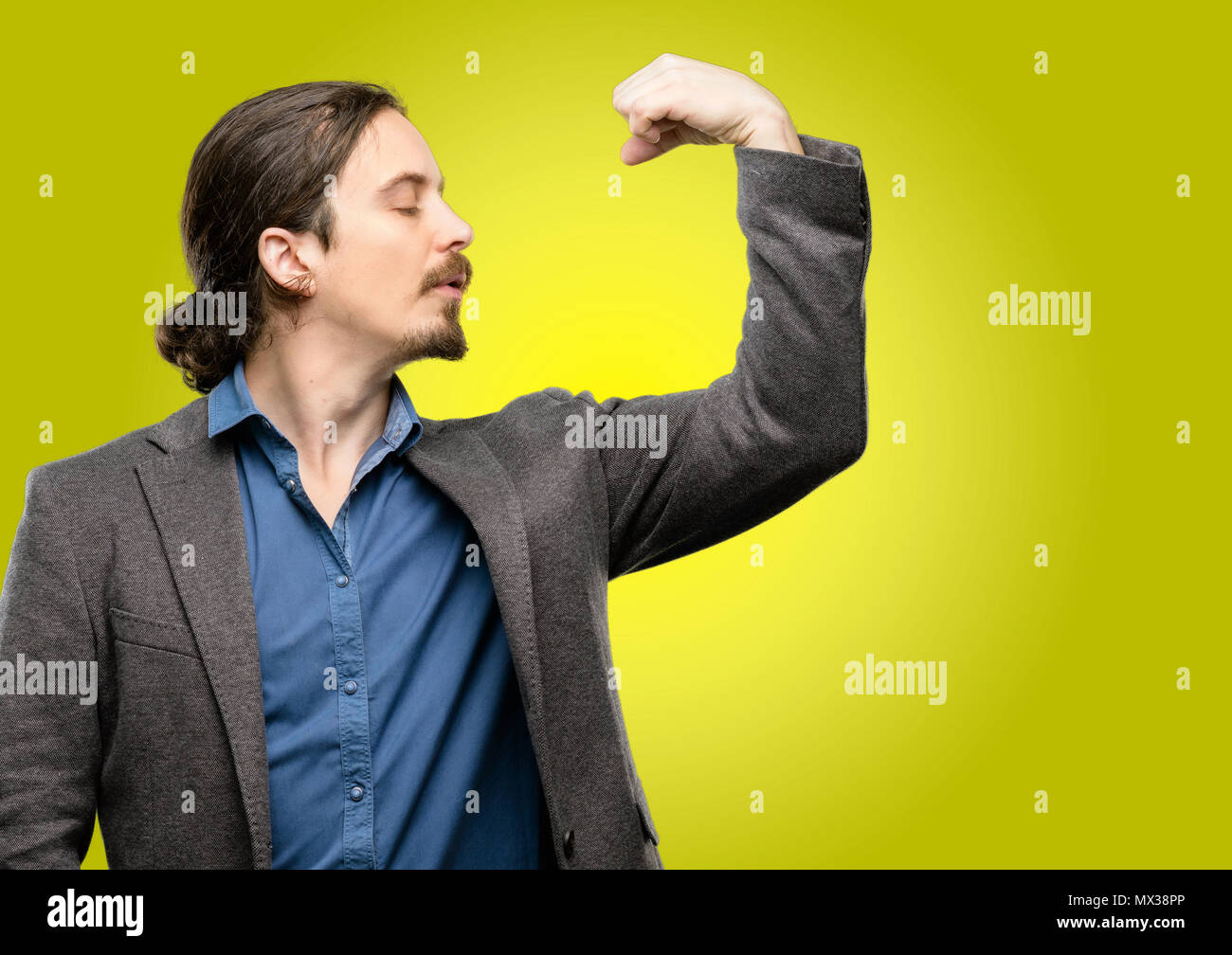 Handsome young man pointing biceps expressing strength and gym concept ...