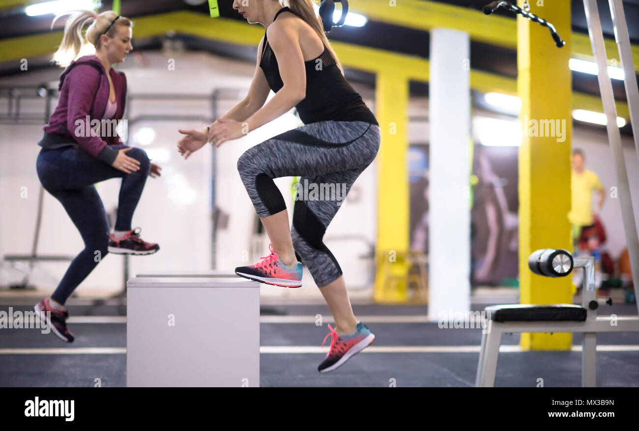 group of young healthy athletic people training jumping on fit box at ...