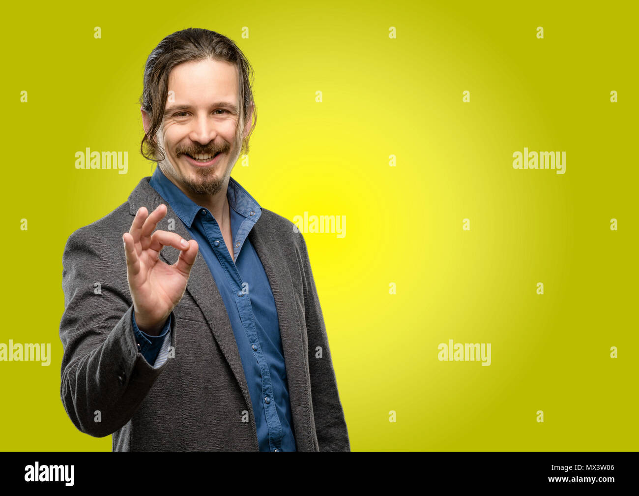Handsome young man doing ok sign with hand, approve gesture Stock Photo ...
