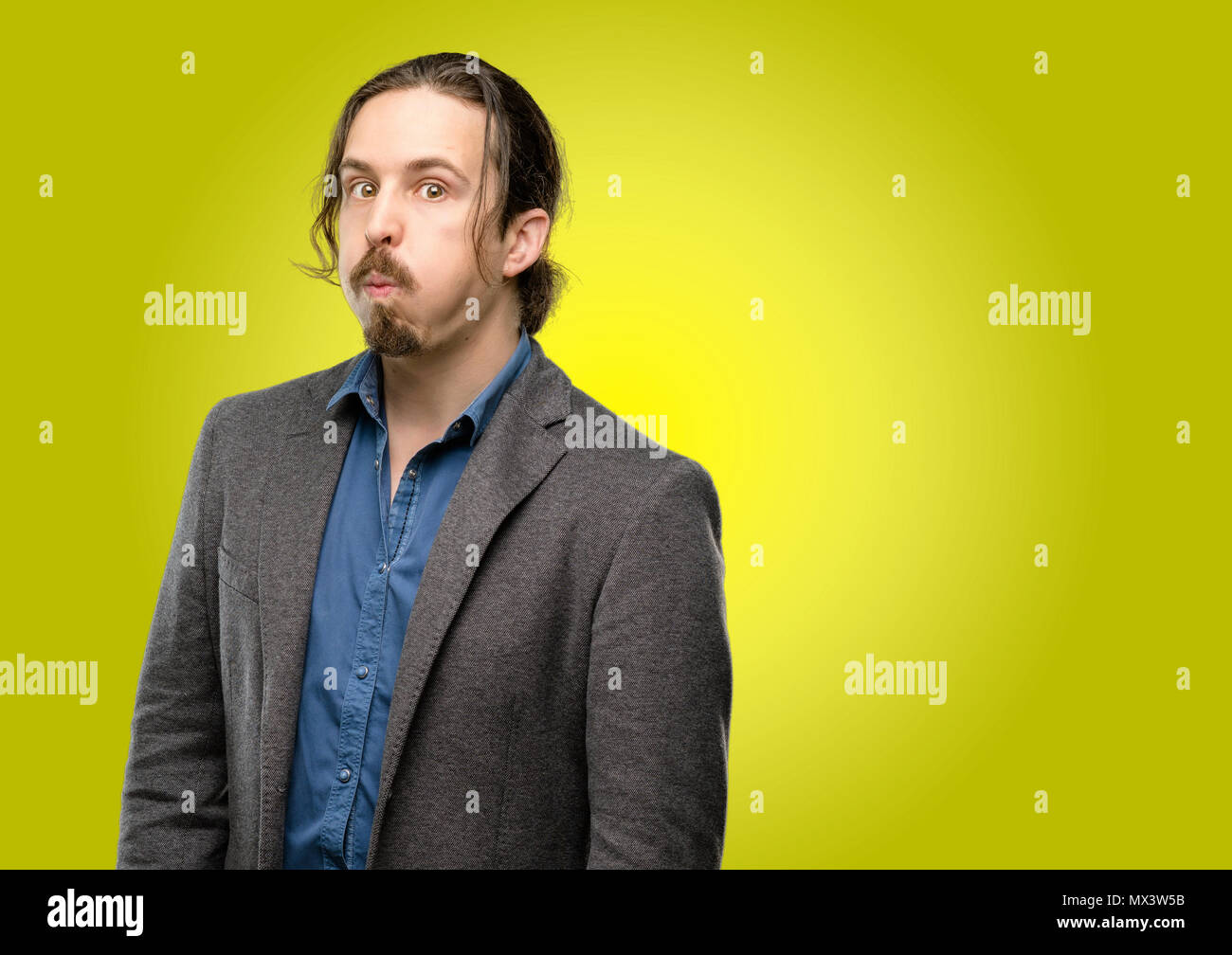 Handsome young man puffing out cheeks, having fun making funny face ...