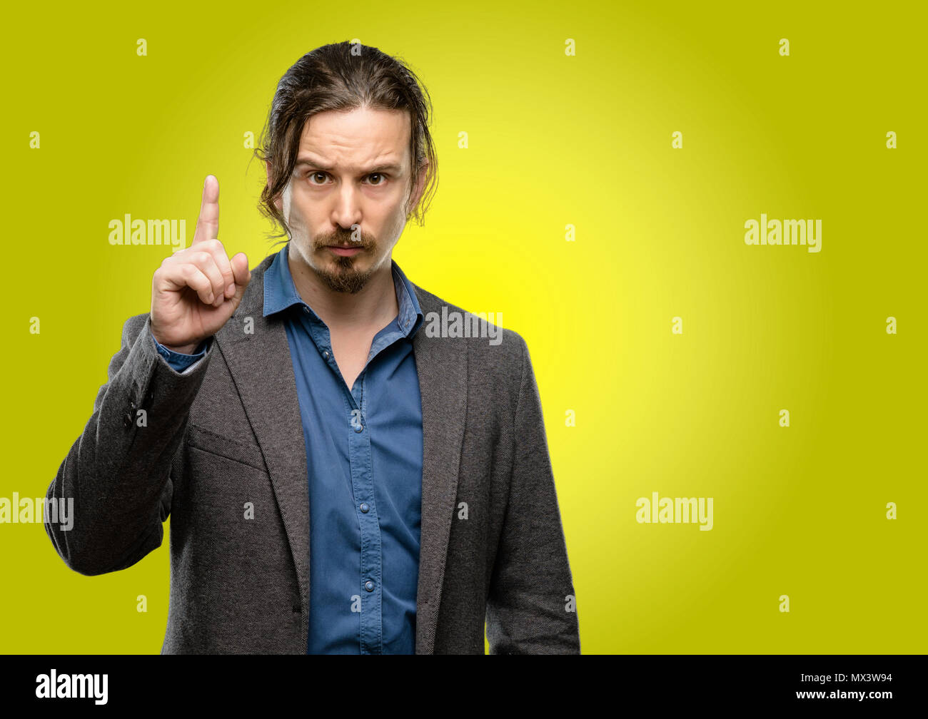 Handsome young man raising his finger, the number one Stock Photo - Alamy