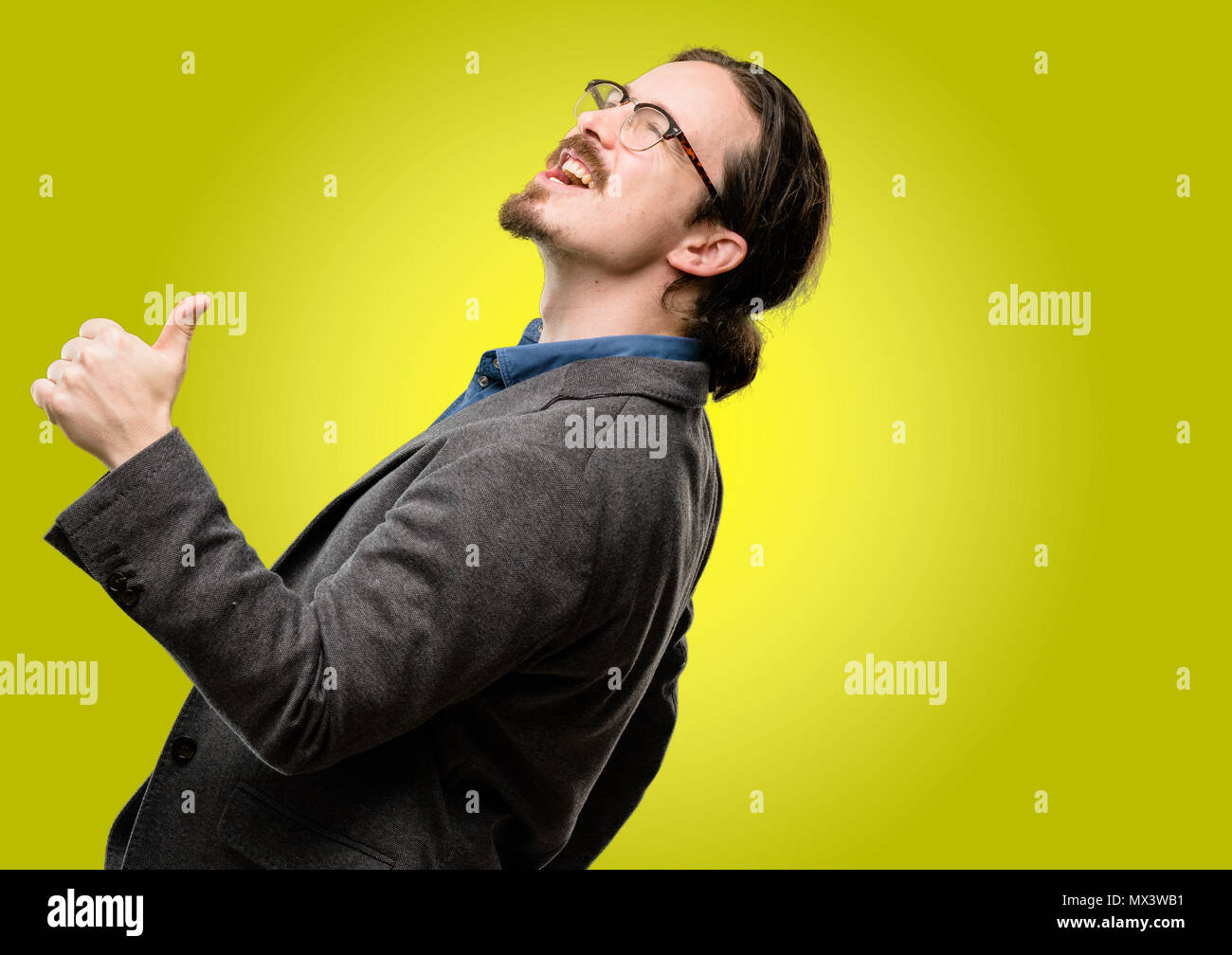 Handsome young man smiling broadly showing thumbs up gesture to camera ...