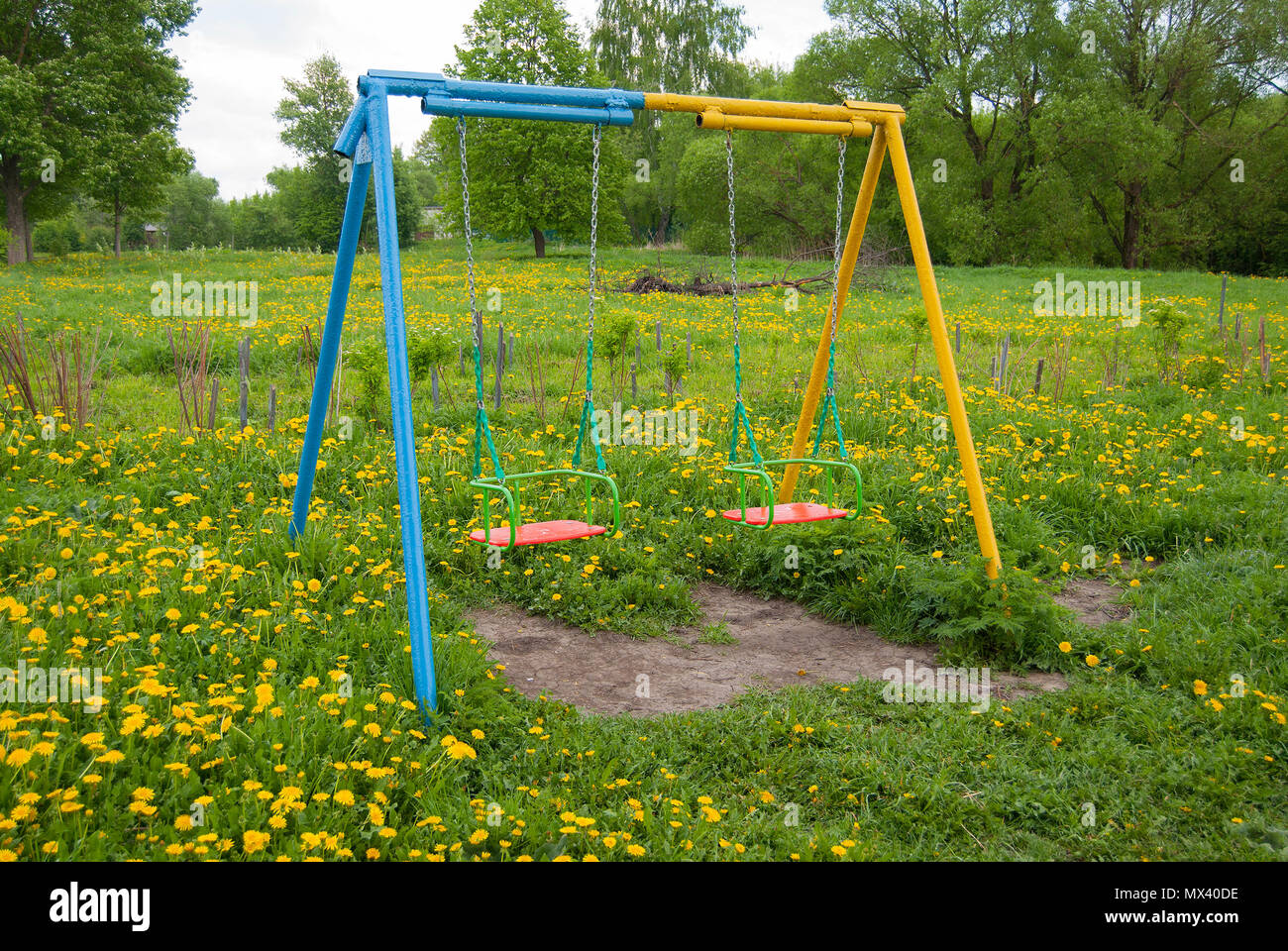 Swings for children, empty, yellow-blue, against a background of bright ...