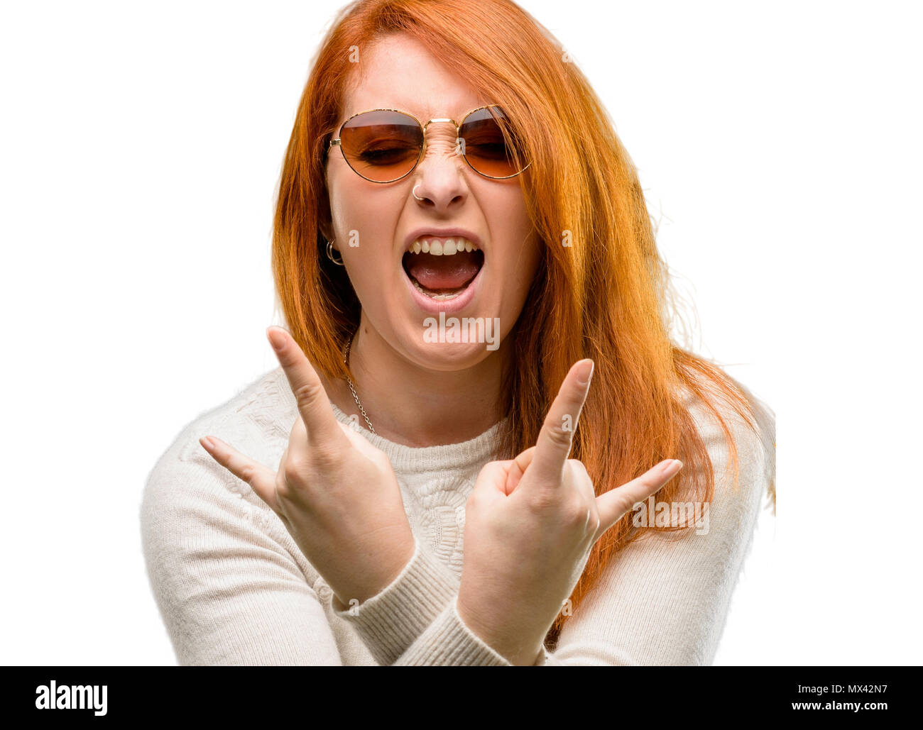 Beautiful young redhead woman making rock symbol with hands, shouting ...