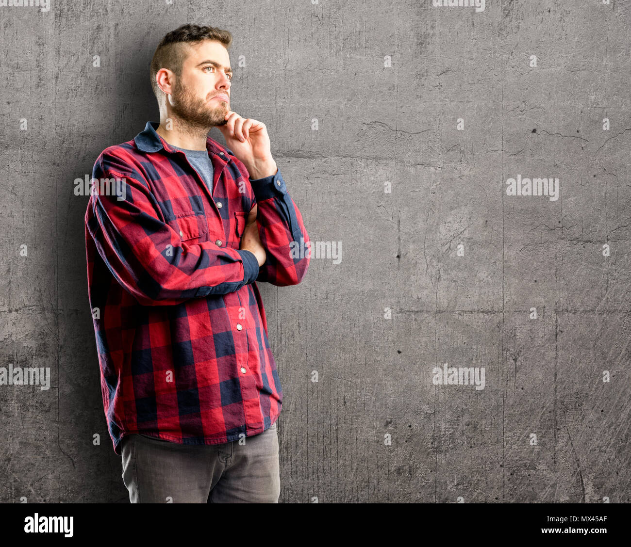 Young handsome man thinking and looking up expressing doubt and wonder ...