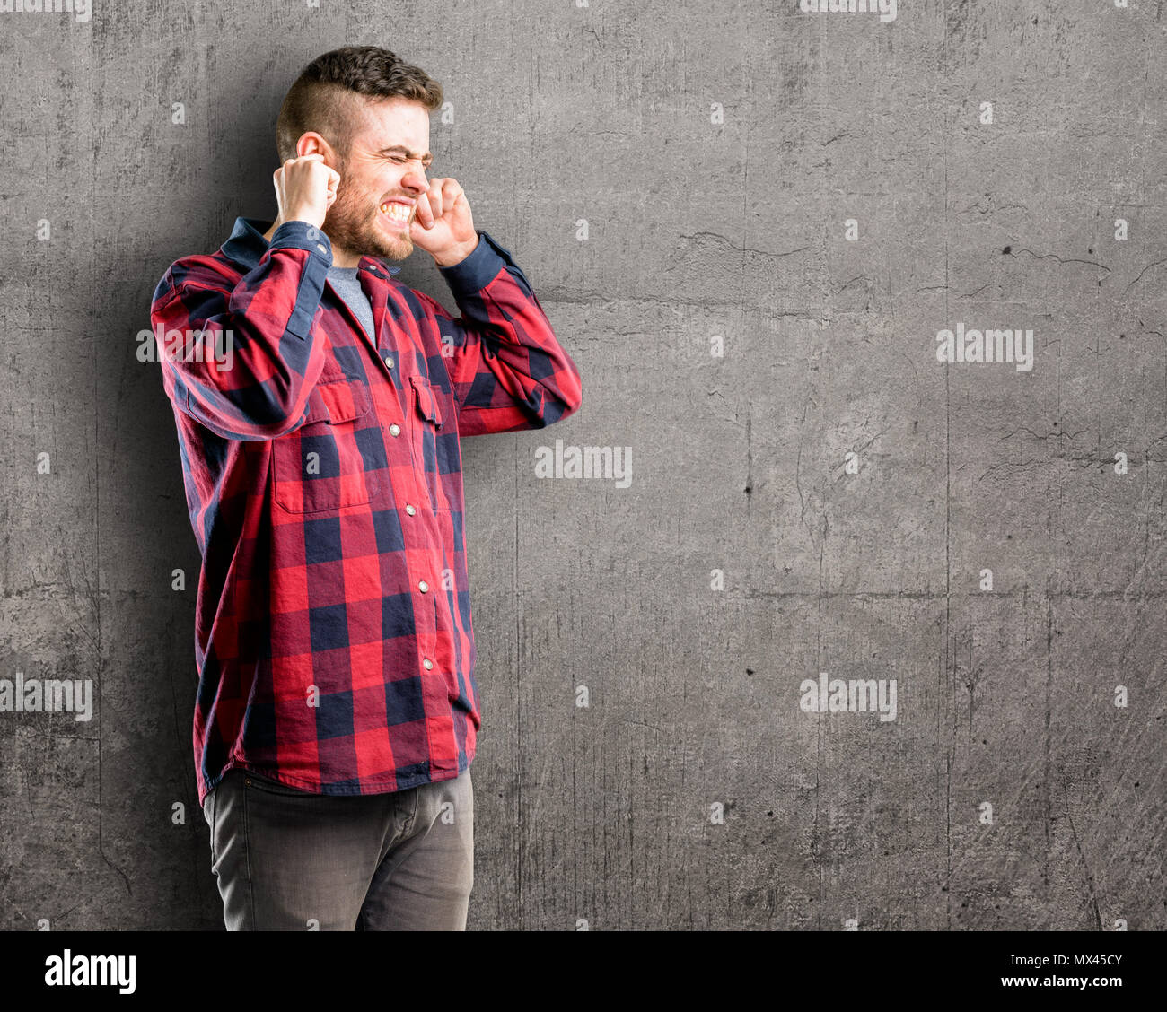 Young handsome man covering ears ignoring annoying loud noise, plugs ...