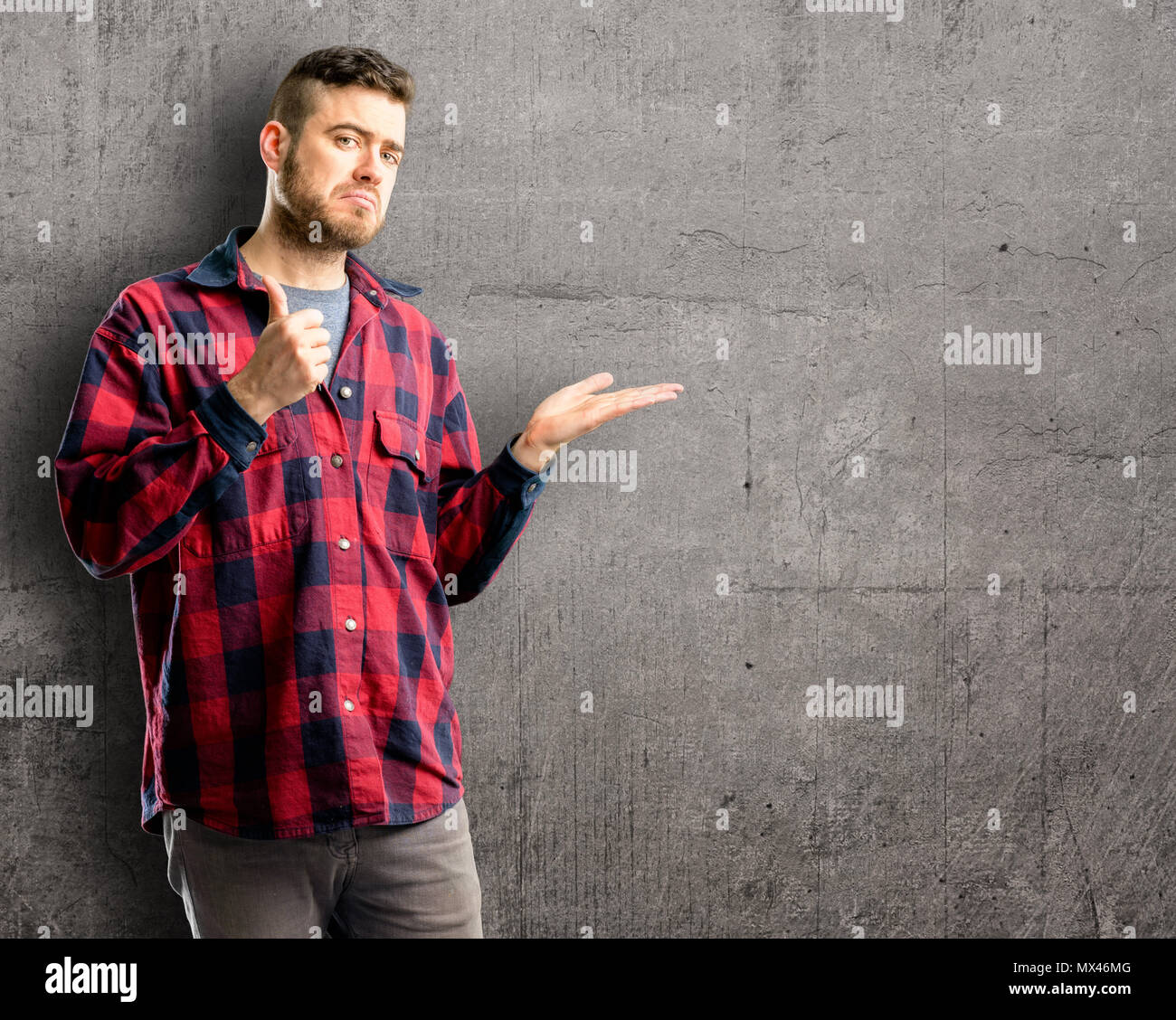 Young handsome man thumb up holding something in his empty hand and ...