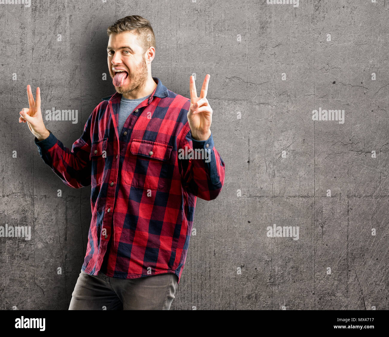 Young handsome man looking at camera showing tong and making victory ...
