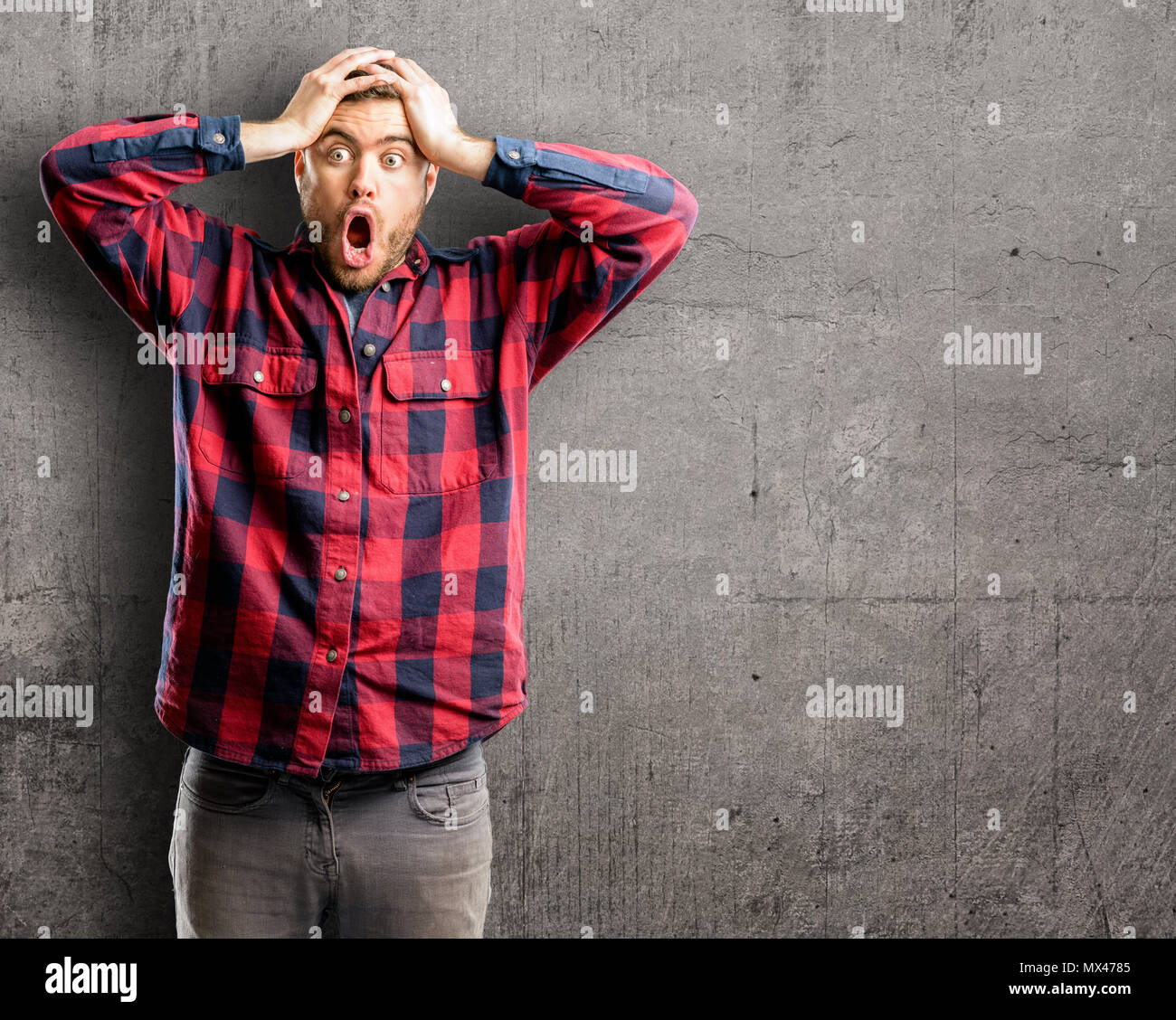 Young handsome man stressful keeping hands on head, terrified in panic ...