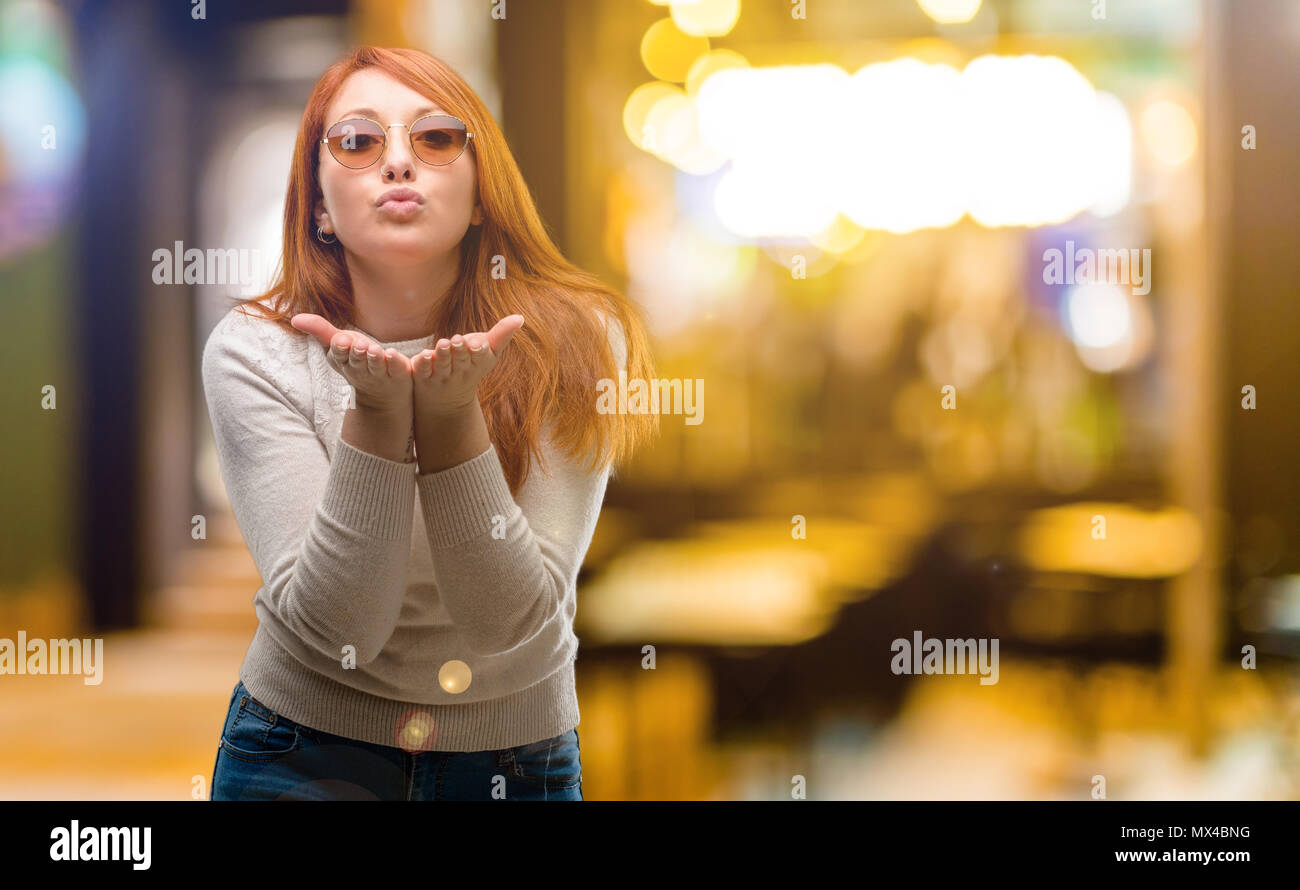 Beautiful young redhead woman expressing love, blows kiss at camera ...
