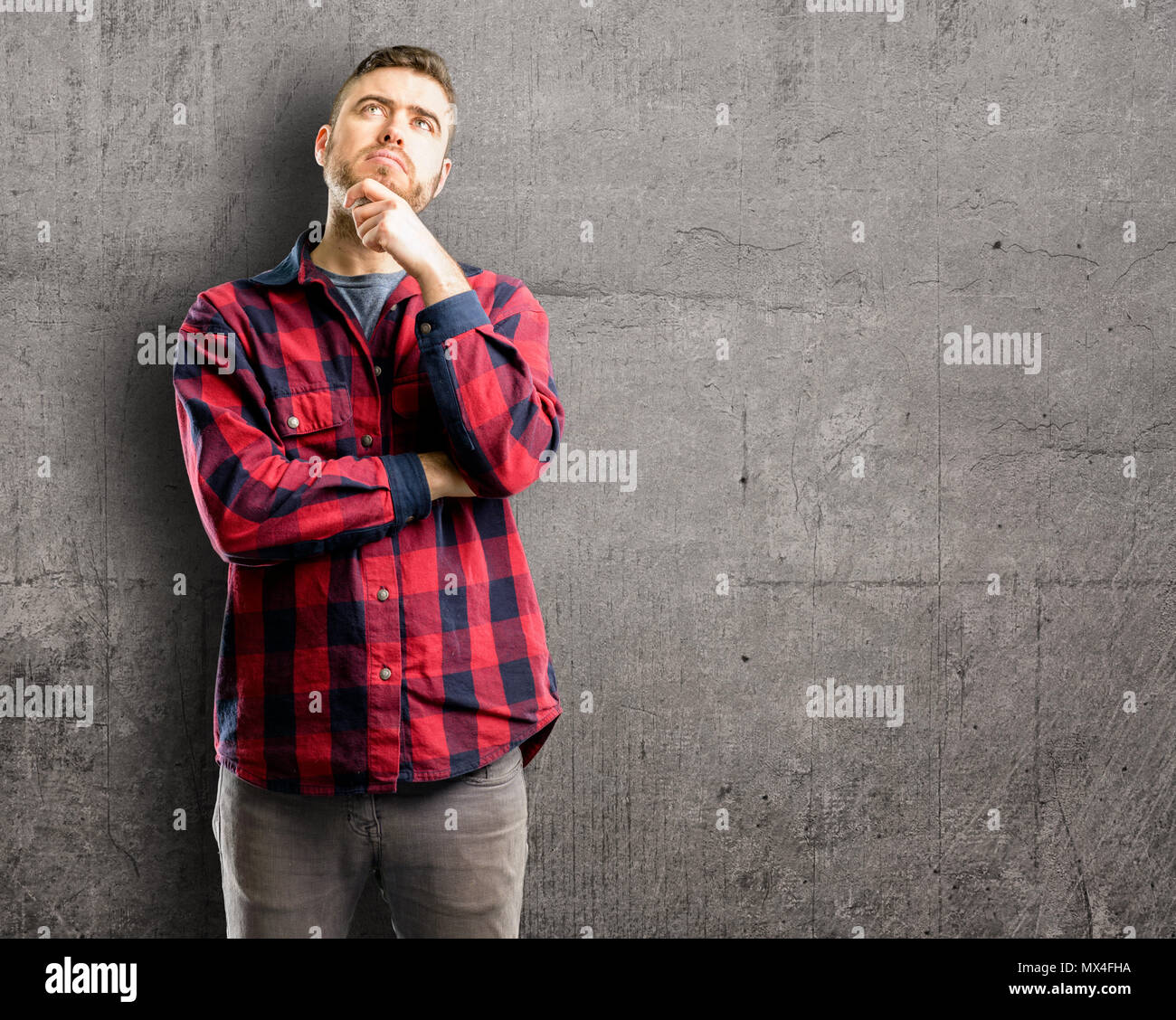 Young handsome man thinking and looking up expressing doubt and wonder ...