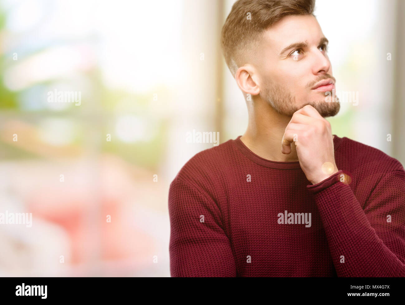 Handsome young man thinking and looking up expressing doubt and wonder ...