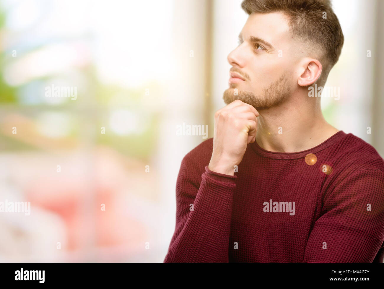Handsome young man thinking and looking up expressing doubt and wonder ...