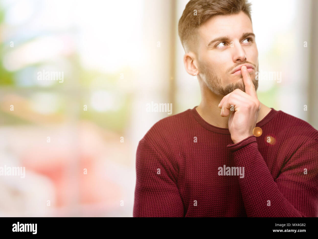 Handsome young man thinking and looking up expressing doubt and wonder ...