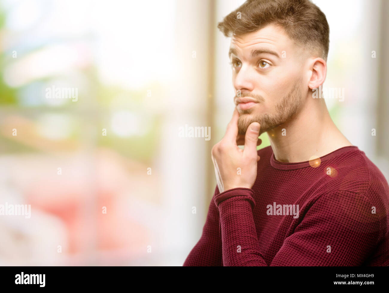 Handsome young man thinking and looking up expressing doubt and wonder ...