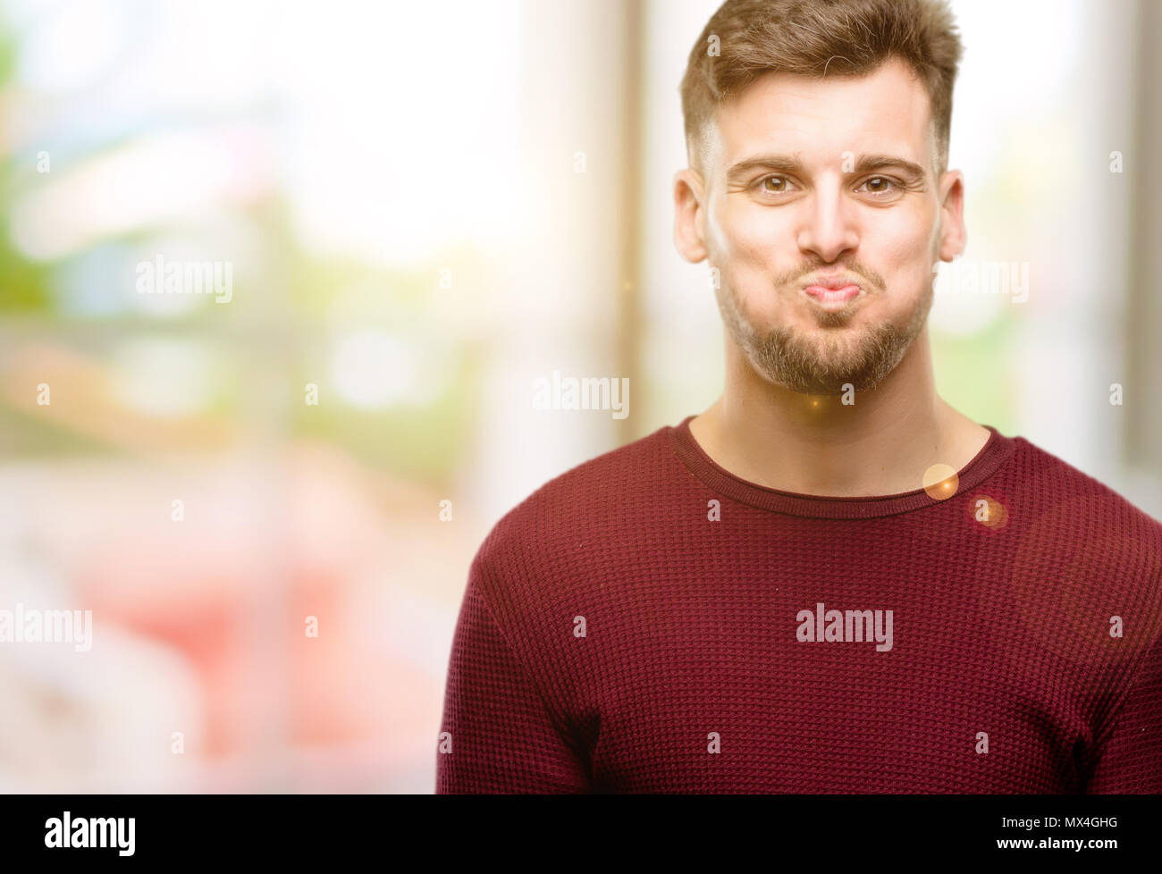 Handsome young man puffing out cheeks, having fun making funny face ...