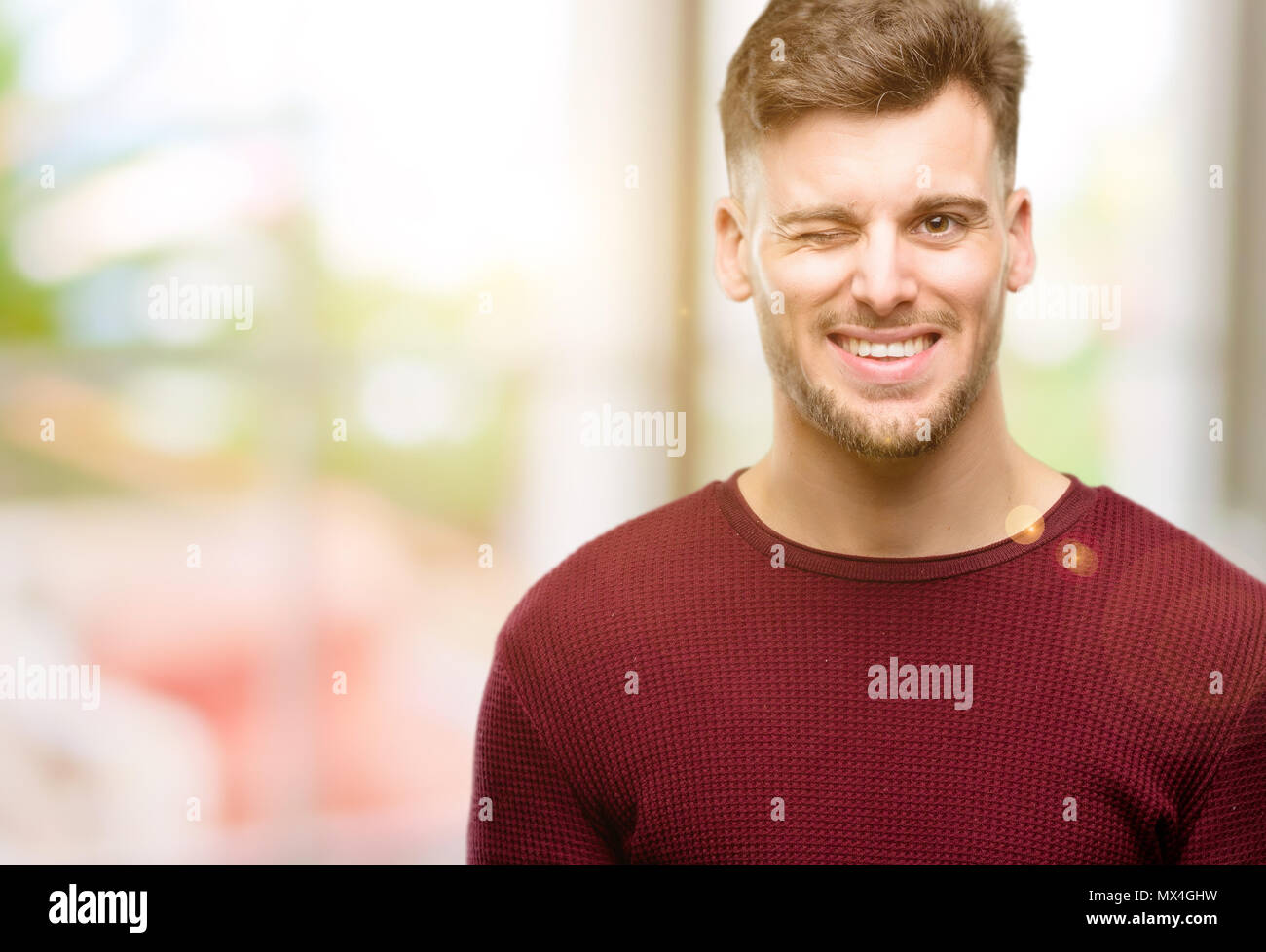 Handsome young man blinking eyes with happy gesture Stock Photo - Alamy