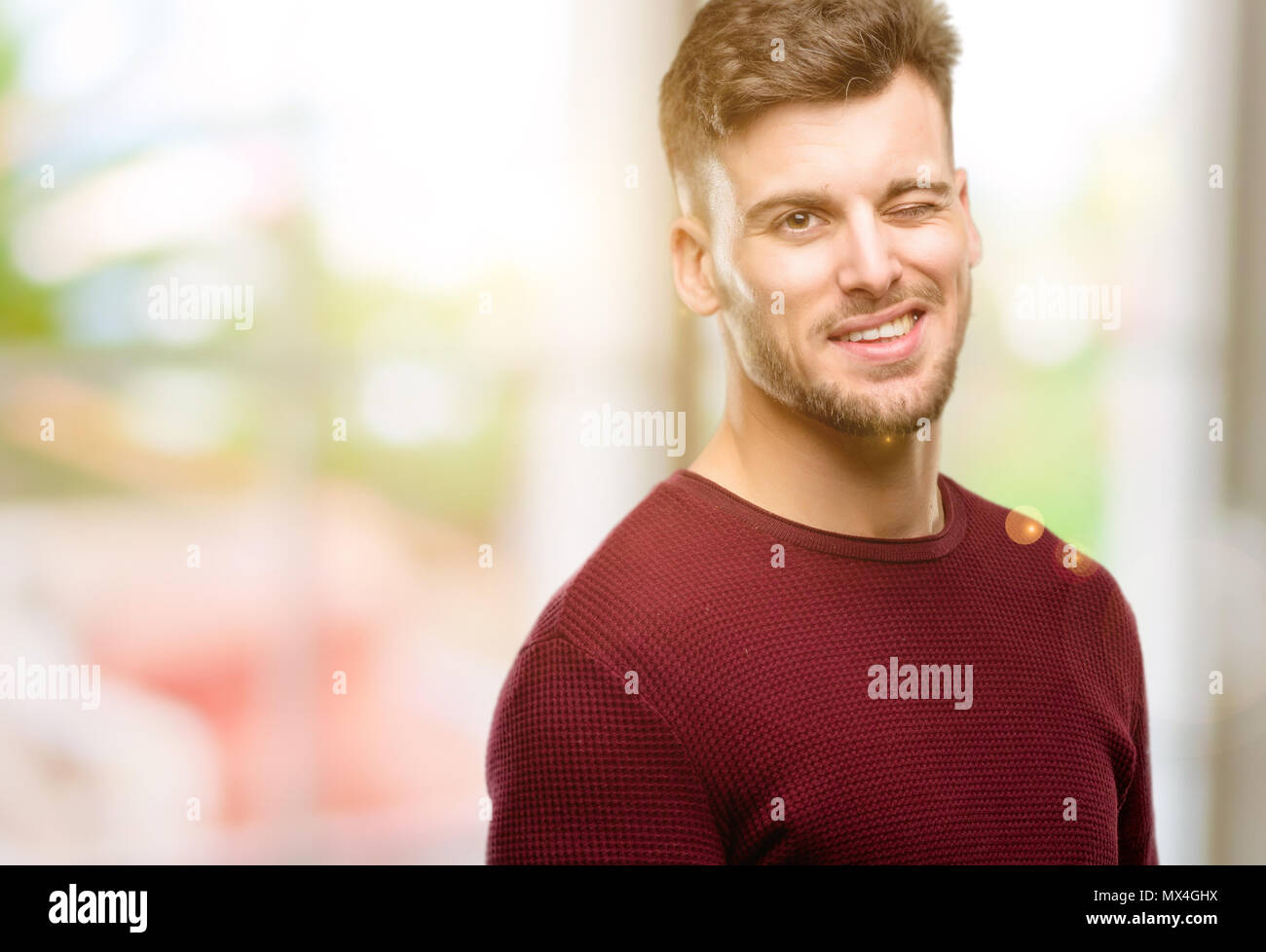 Handsome young man blinking eyes with happy gesture Stock Photo - Alamy