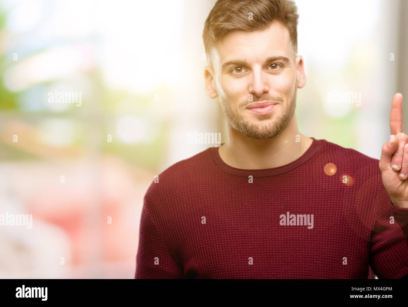 Handsome young man raising his finger, the number one Stock Photo - Alamy