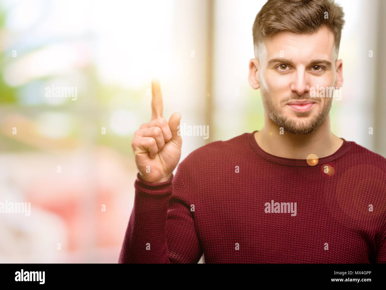 Handsome young man raising his finger, the number one Stock Photo - Alamy
