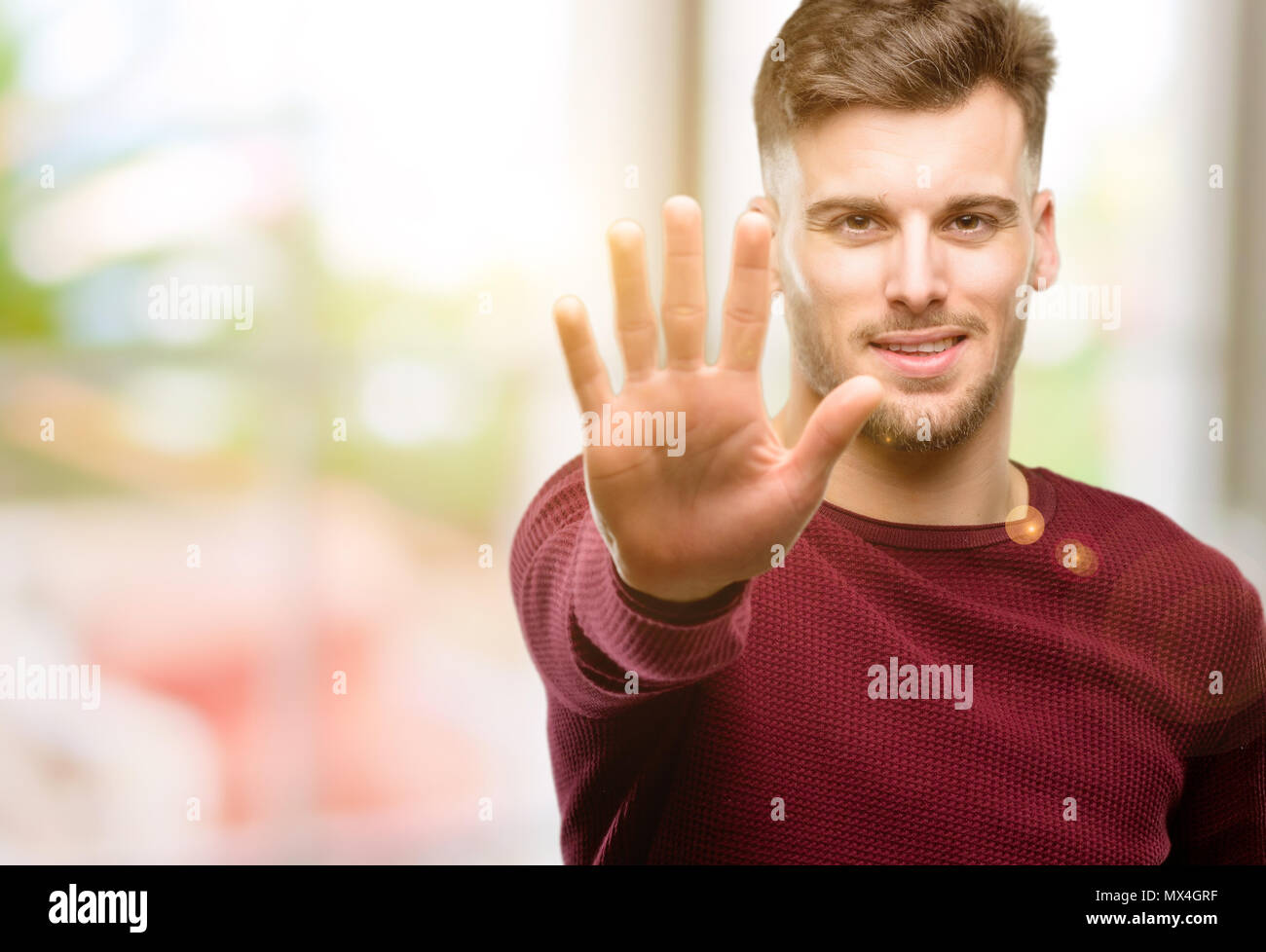 Handsome young man raising his finger, is the number five Stock Photo ...