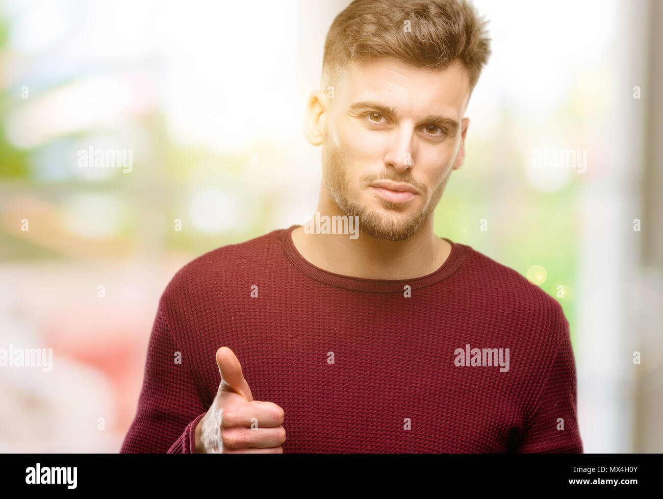 Handsome young man thumb up holding something in his empty hand and ...