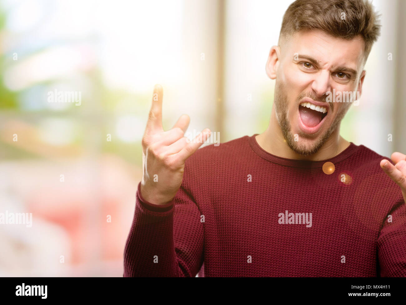Handsome young man making rock symbol with hands, shouting and ...