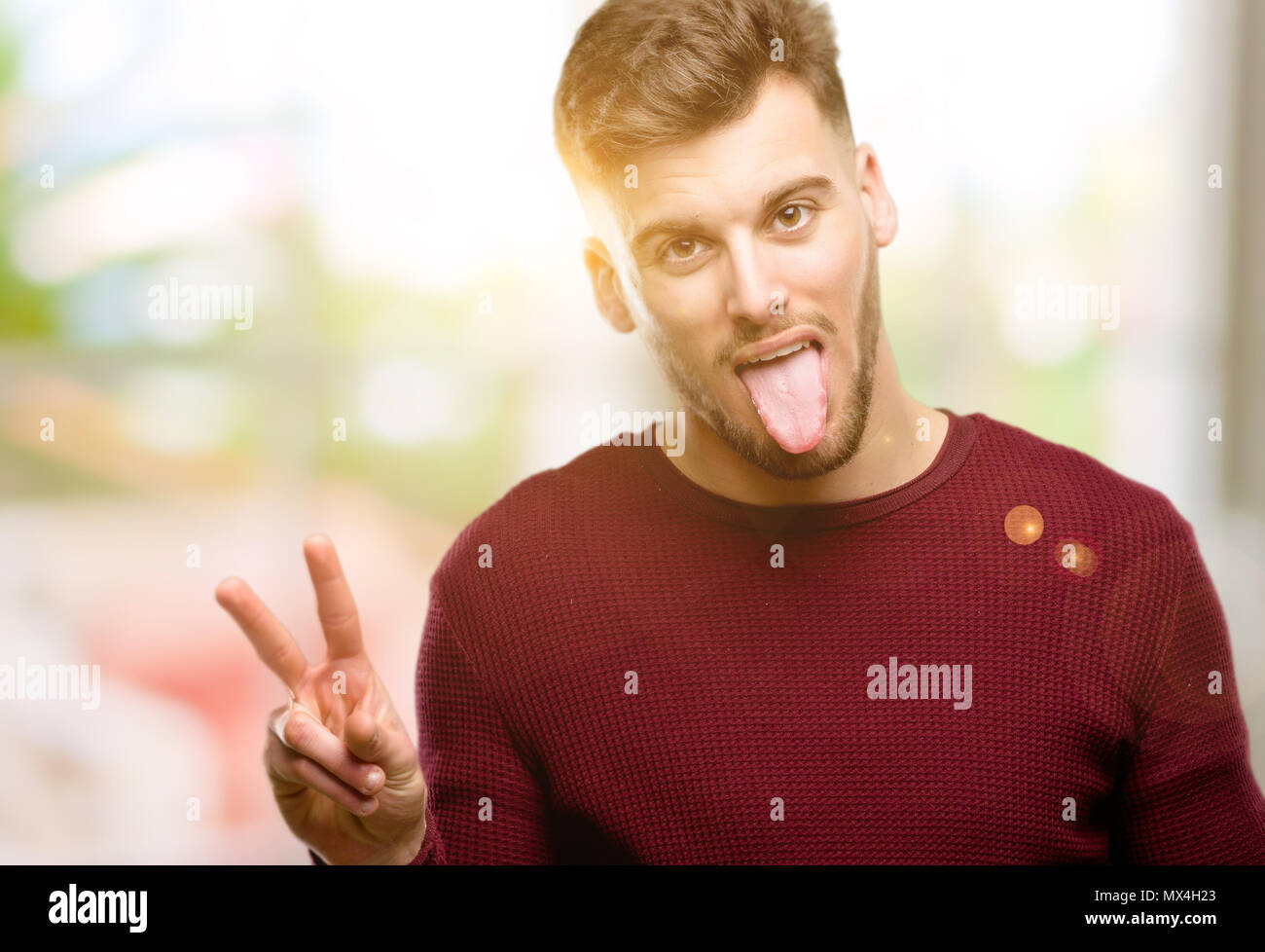 Handsome young man looking at camera showing tong and making victory ...