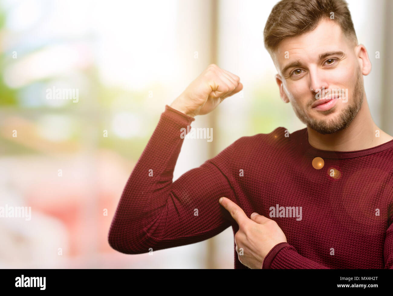Handsome young man pointing biceps expressing strength and gym concept ...
