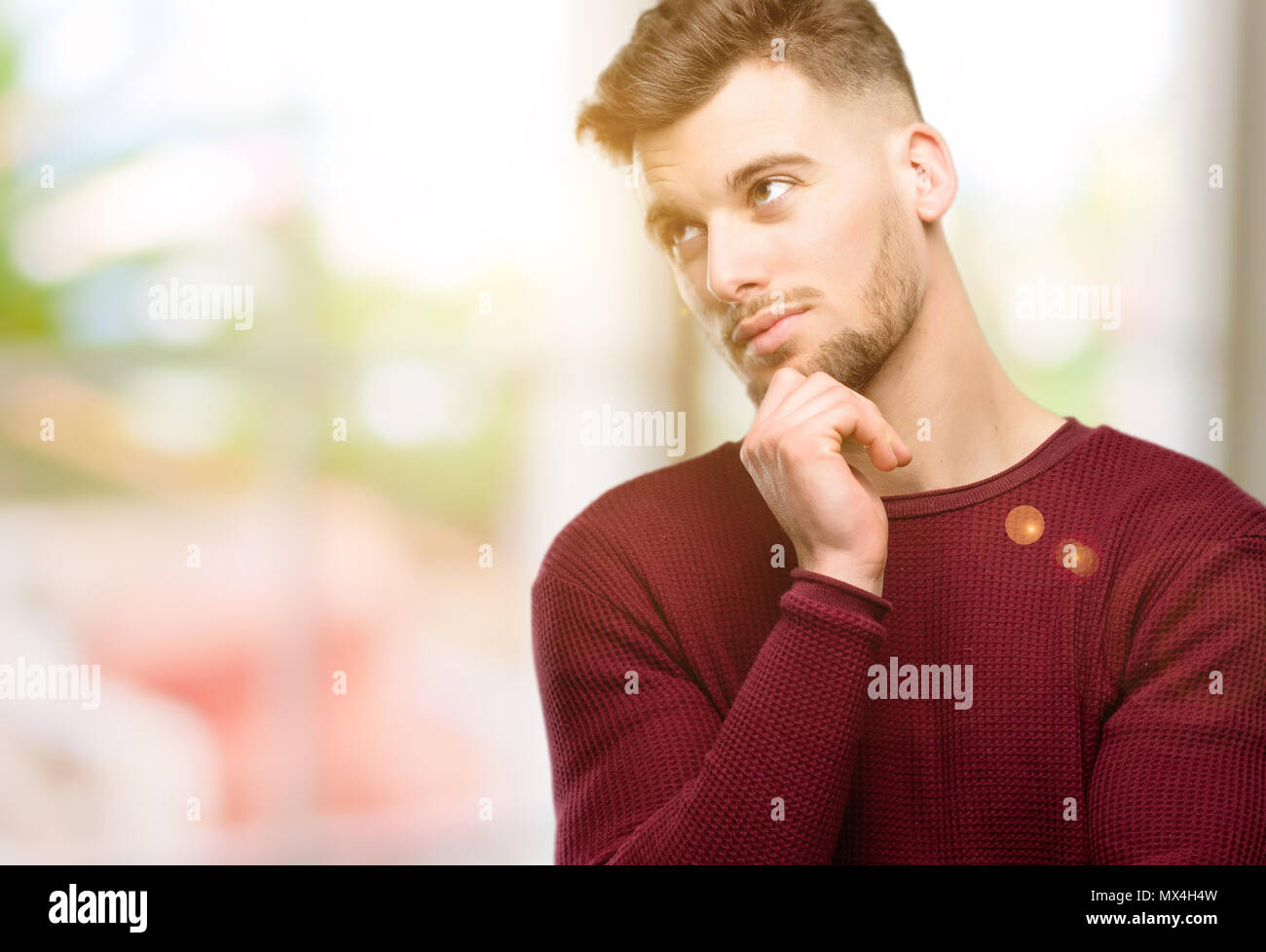 Handsome young man thinking and looking up expressing doubt and wonder ...