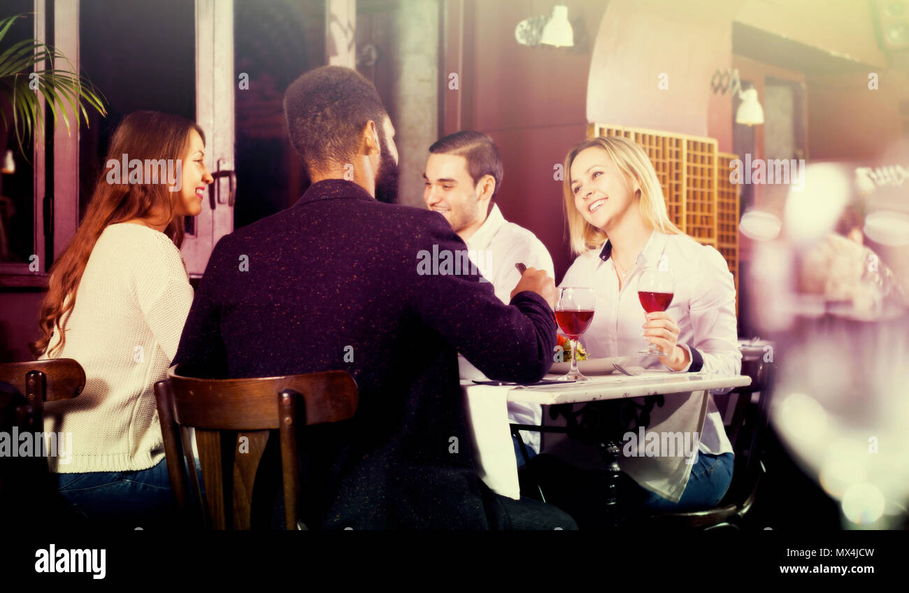 Happy middle class people enjoying food in cafe and talking in interior ...