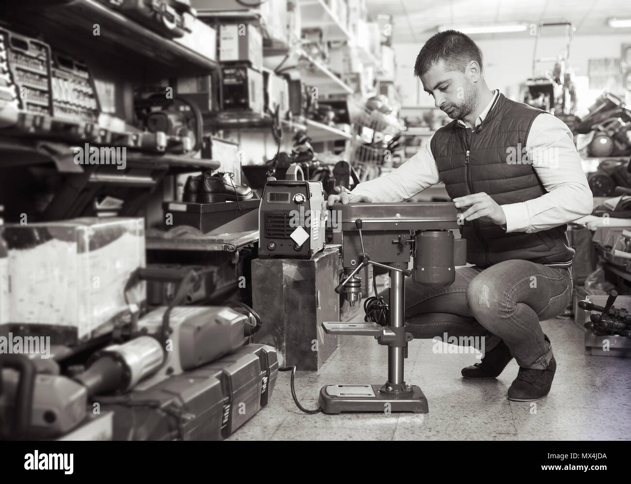 Man is choosing new puncher in tools store Stock Photo - Alamy