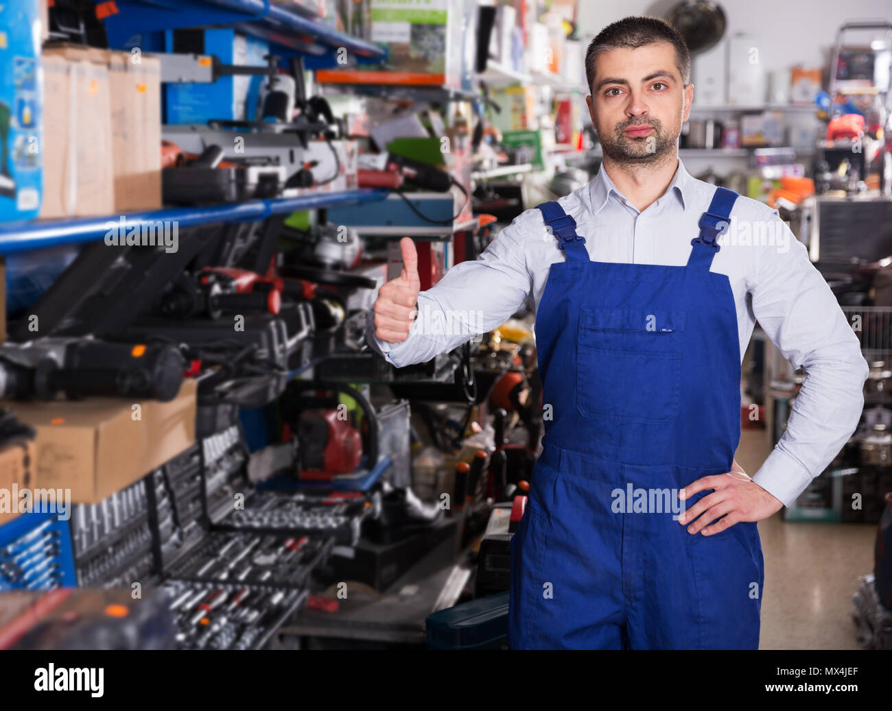 Positive workman in blue coverall is satisfied of shopping in the tools ...