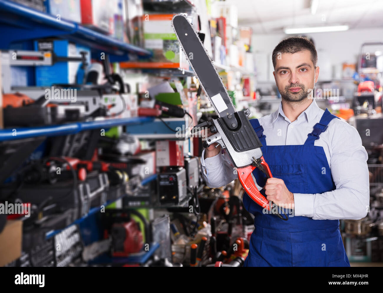 male is standing with new electric saw in tools store Stock Photo - Alamy