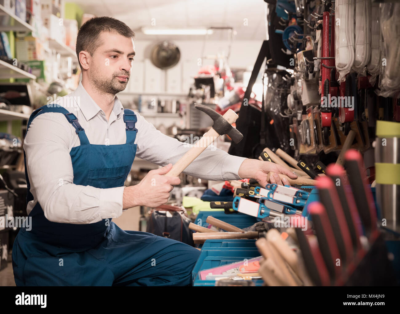 Man is selecting hammer in tools store Stock Photo - Alamy